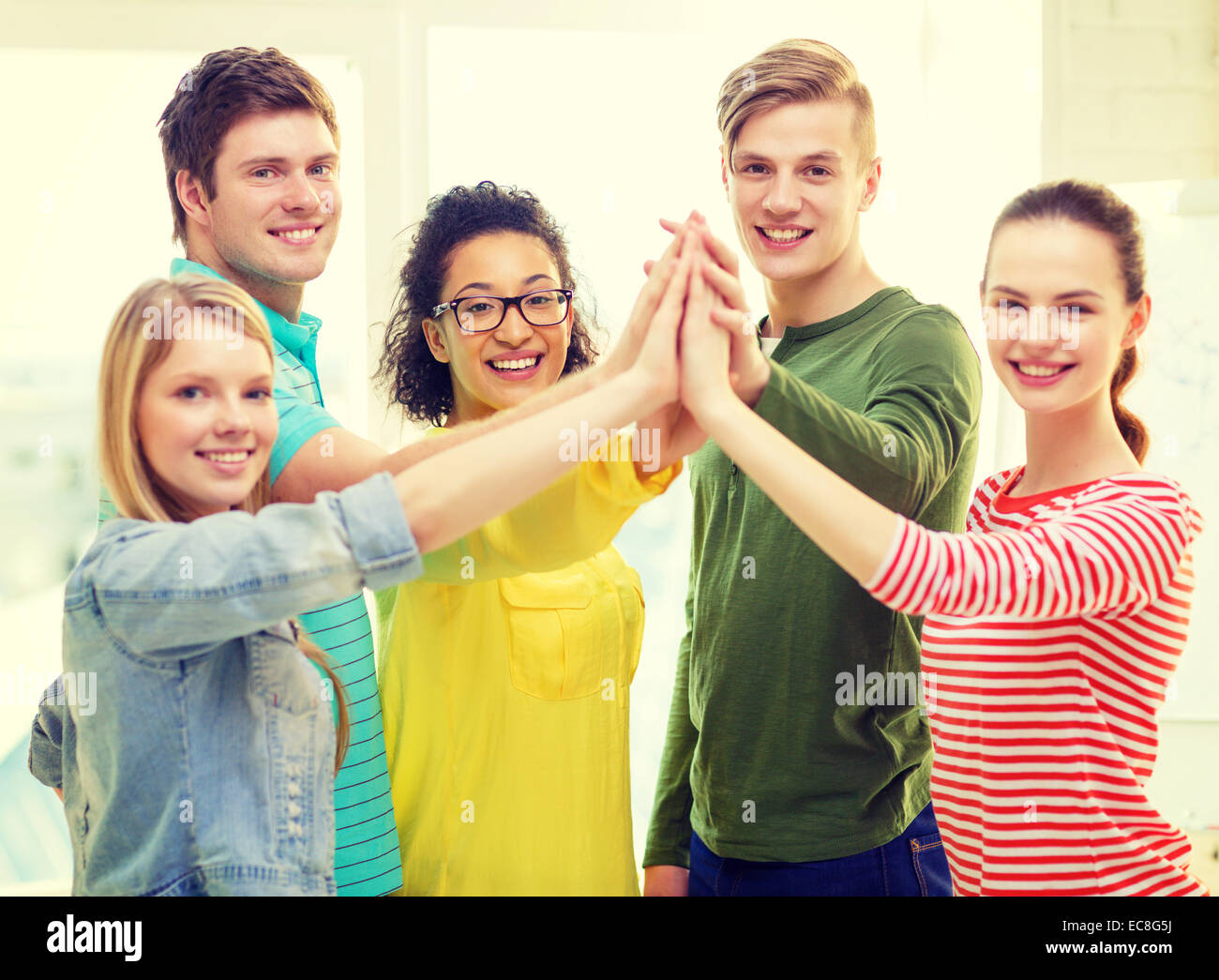 five smiling students giving high five at school Stock Photo - Alamy