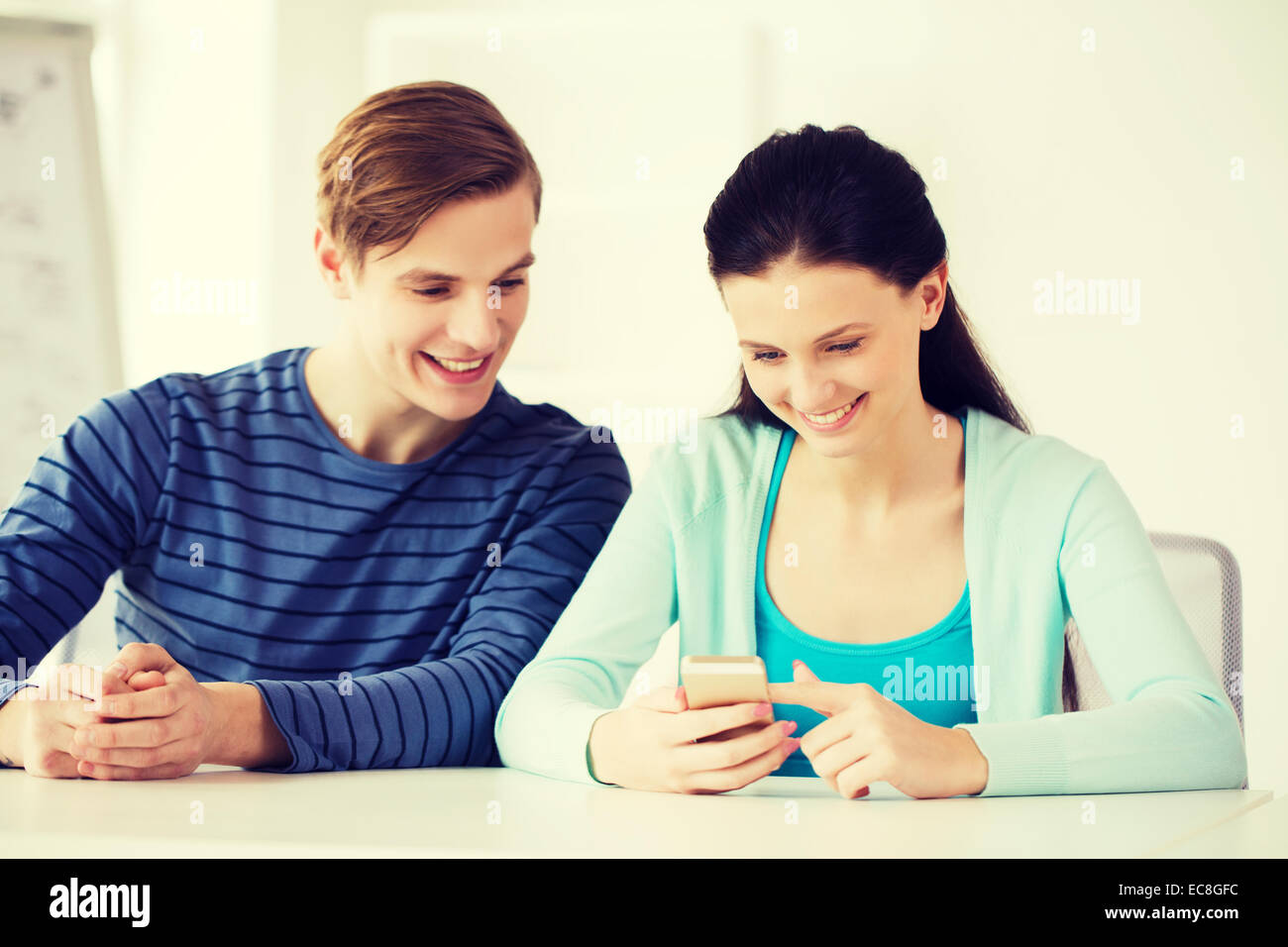 two smiling students with smartphone at school Stock Photo - Alamy