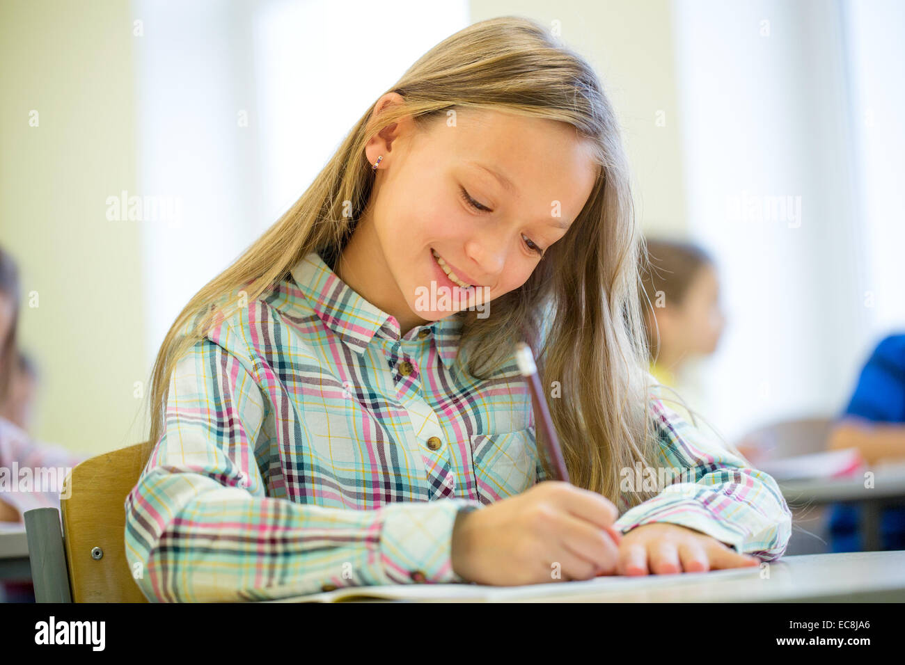 smiling school girl writing test in classroom Stock Photo - Alamy