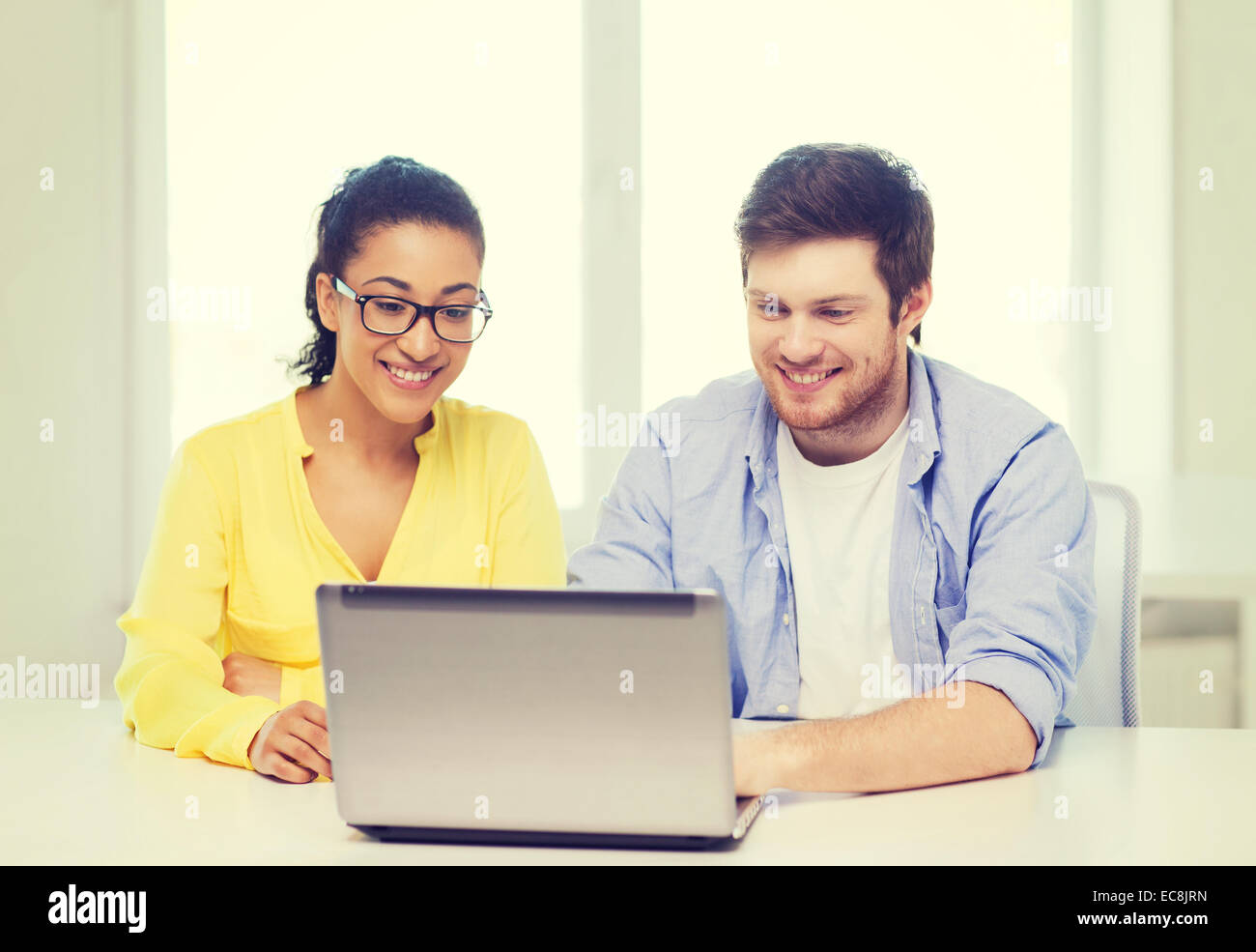 two smiling people with laptop in office Stock Photo - Alamy