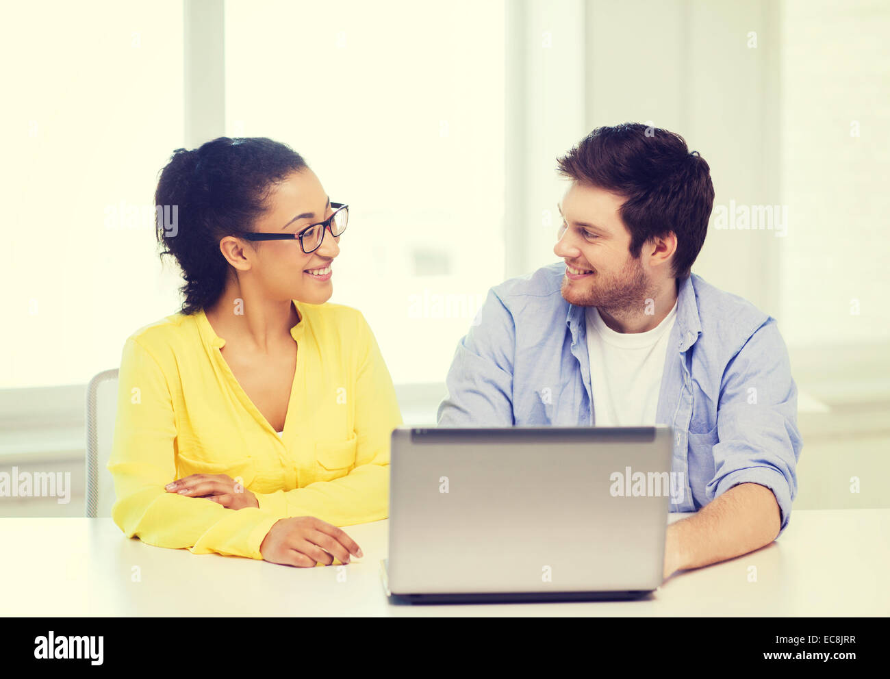 two smiling people with laptop in office Stock Photo - Alamy