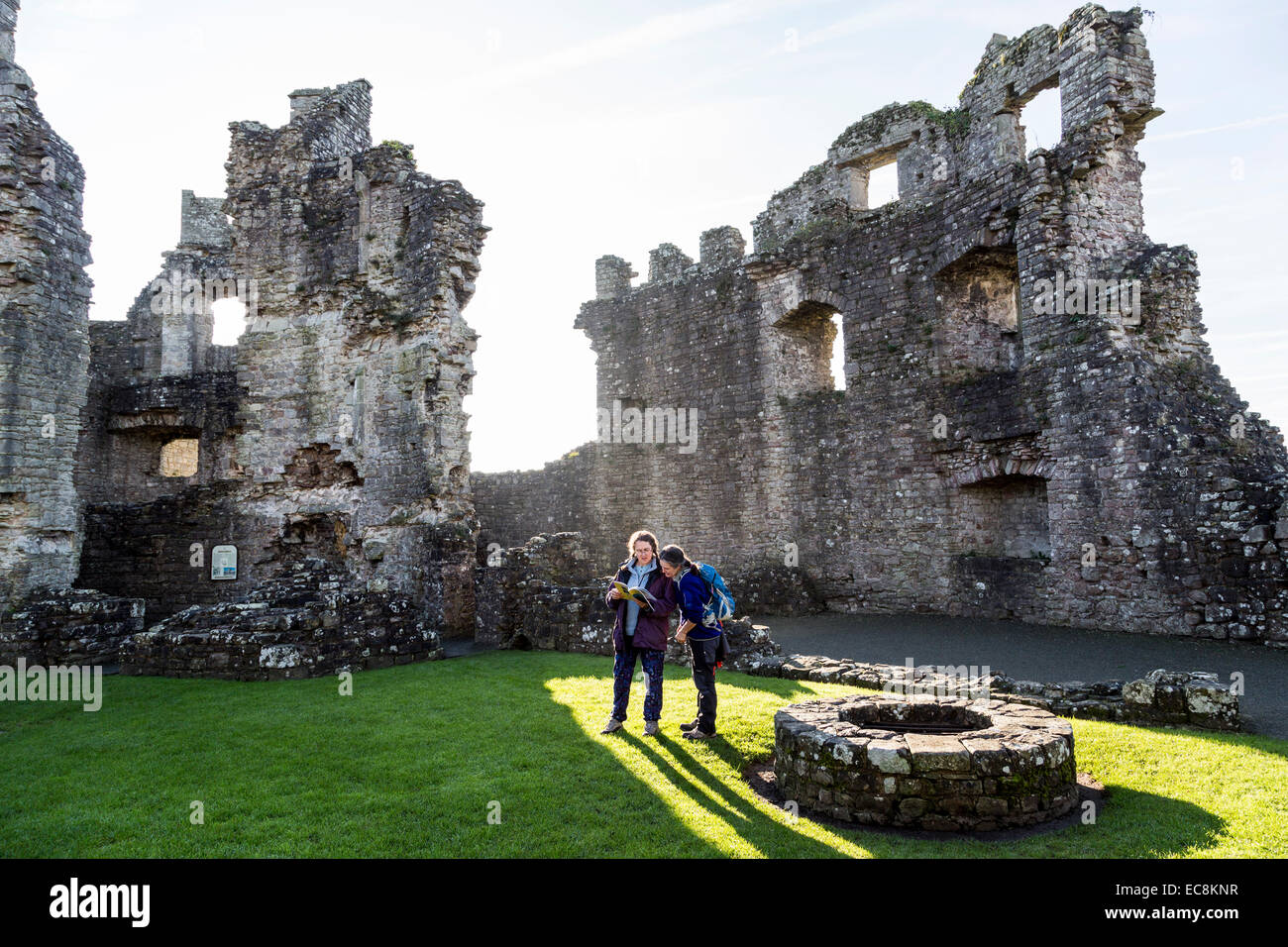 Two women visitors reading a guidebook in the ruin of Coity Castle ...