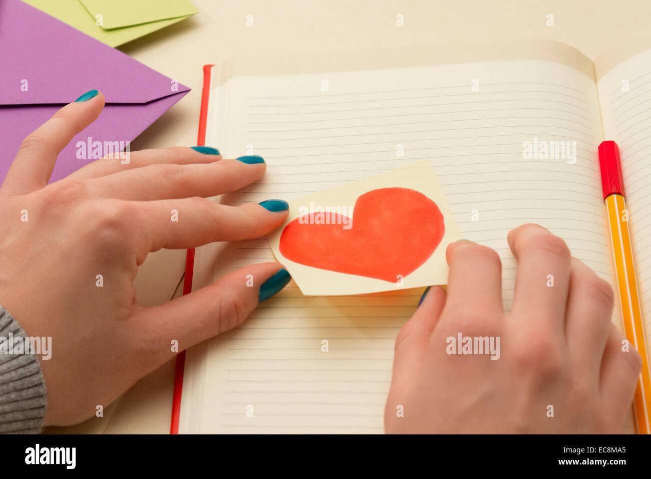 Girl putting a sticky note into notebook Stock Photo - Alamy
