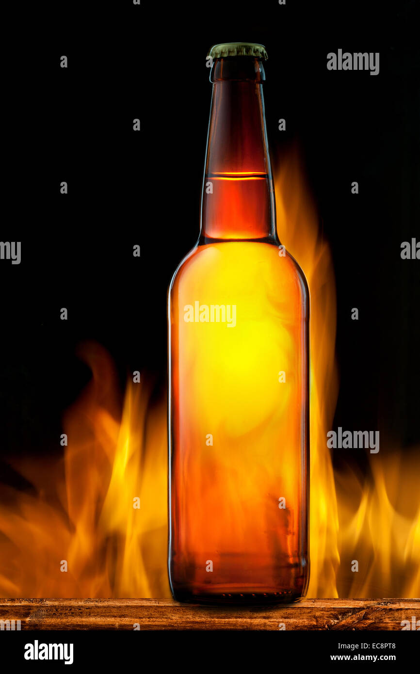 Beer bottle in fire on black Stock Photo - Alamy