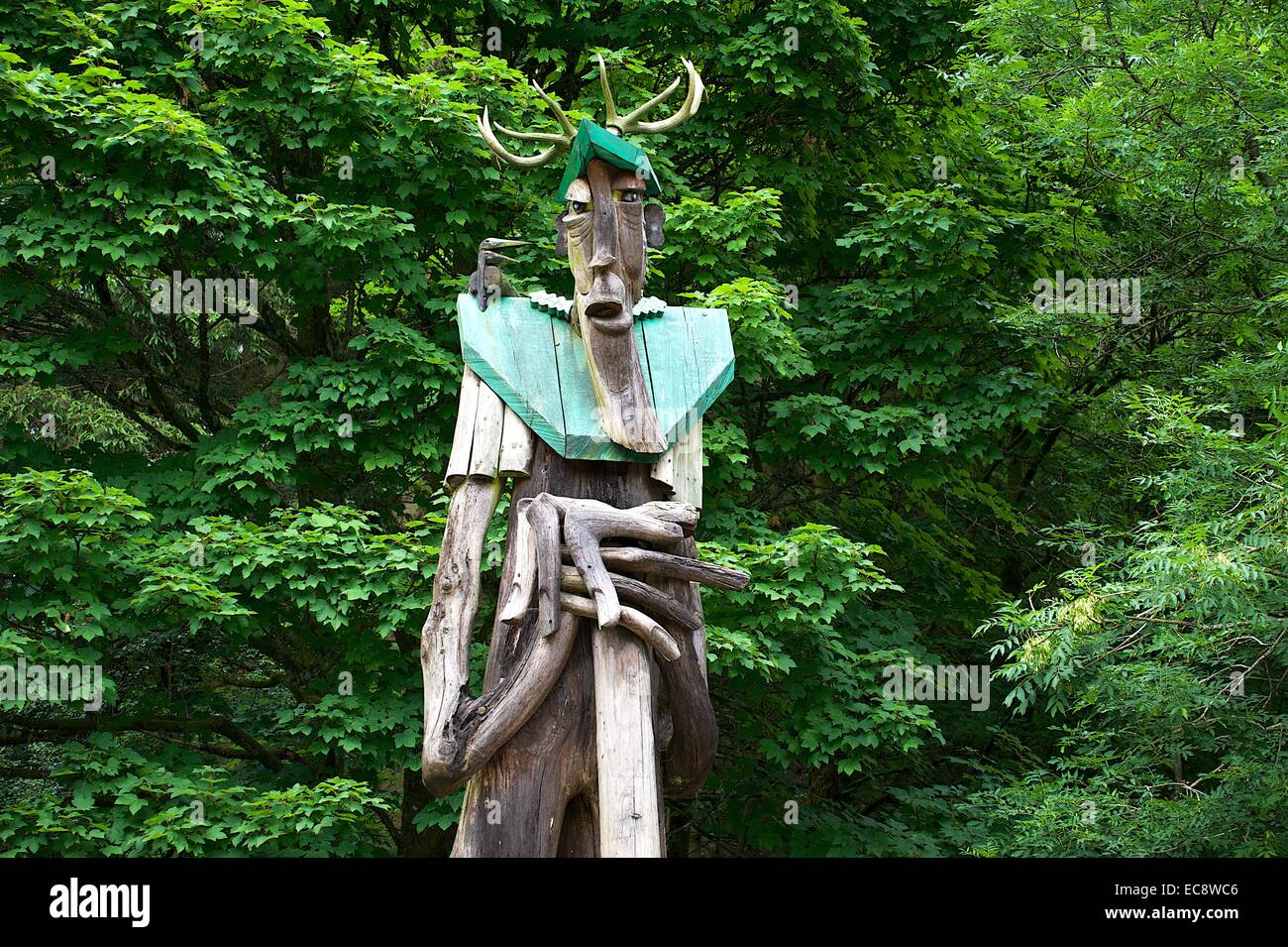 A wooden carved man with antlers stands by a forest Stock Photo - Alamy