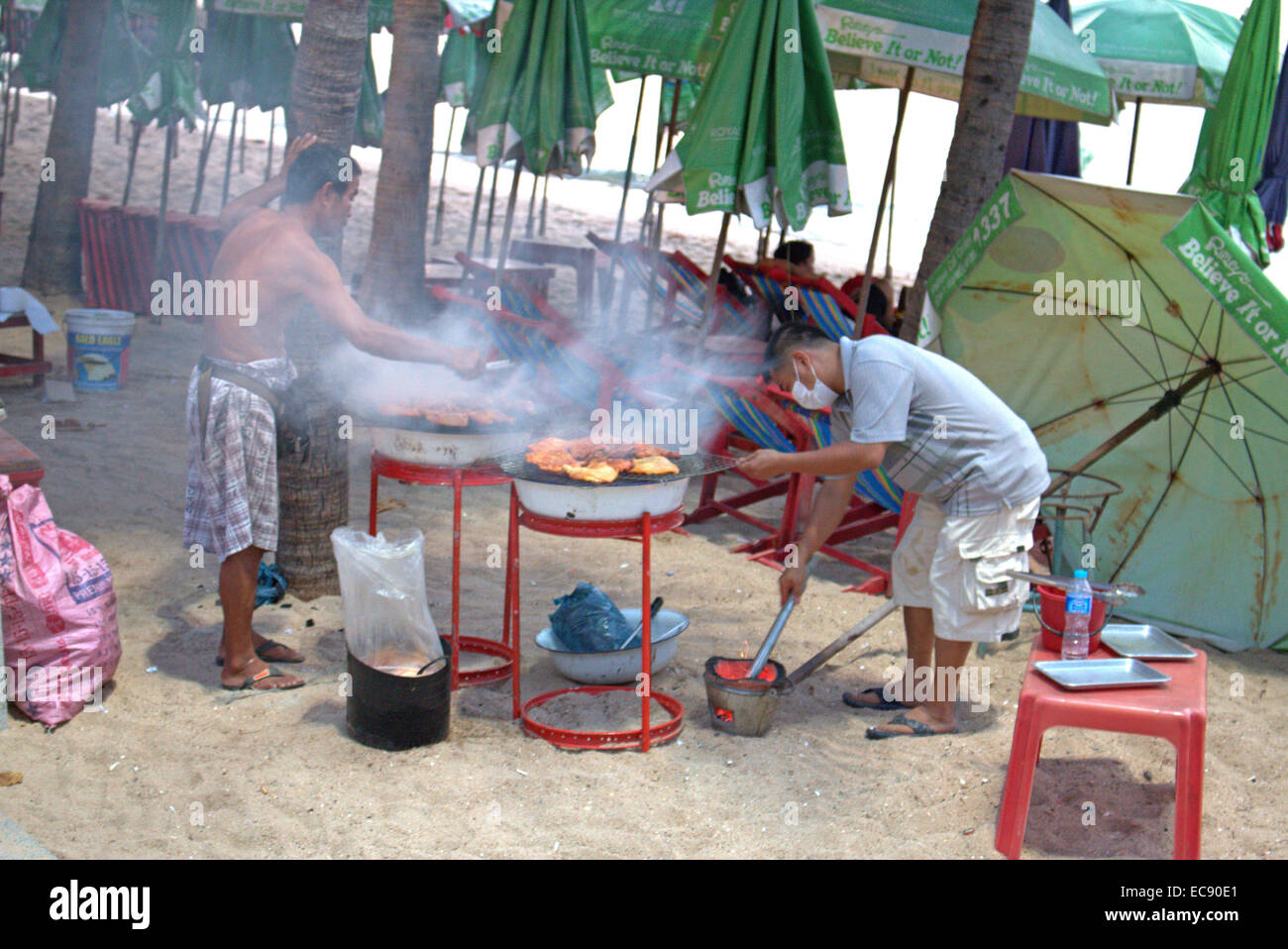 Two people cooking a BBQ on Pattaya beach Stock Photo - Alamy