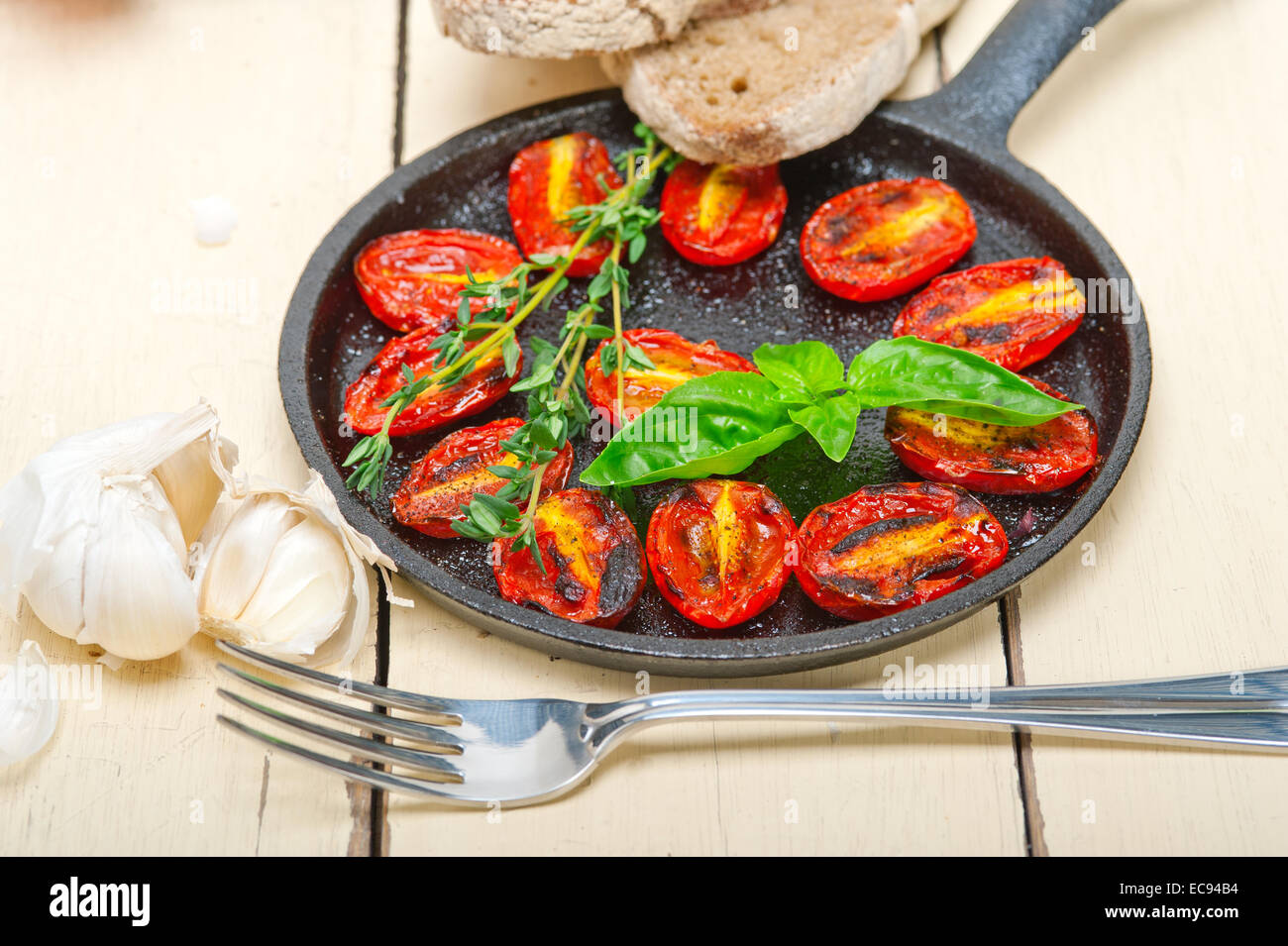 oven baked cherry tomatoes with basil and thyme on a cast iron skillet ...