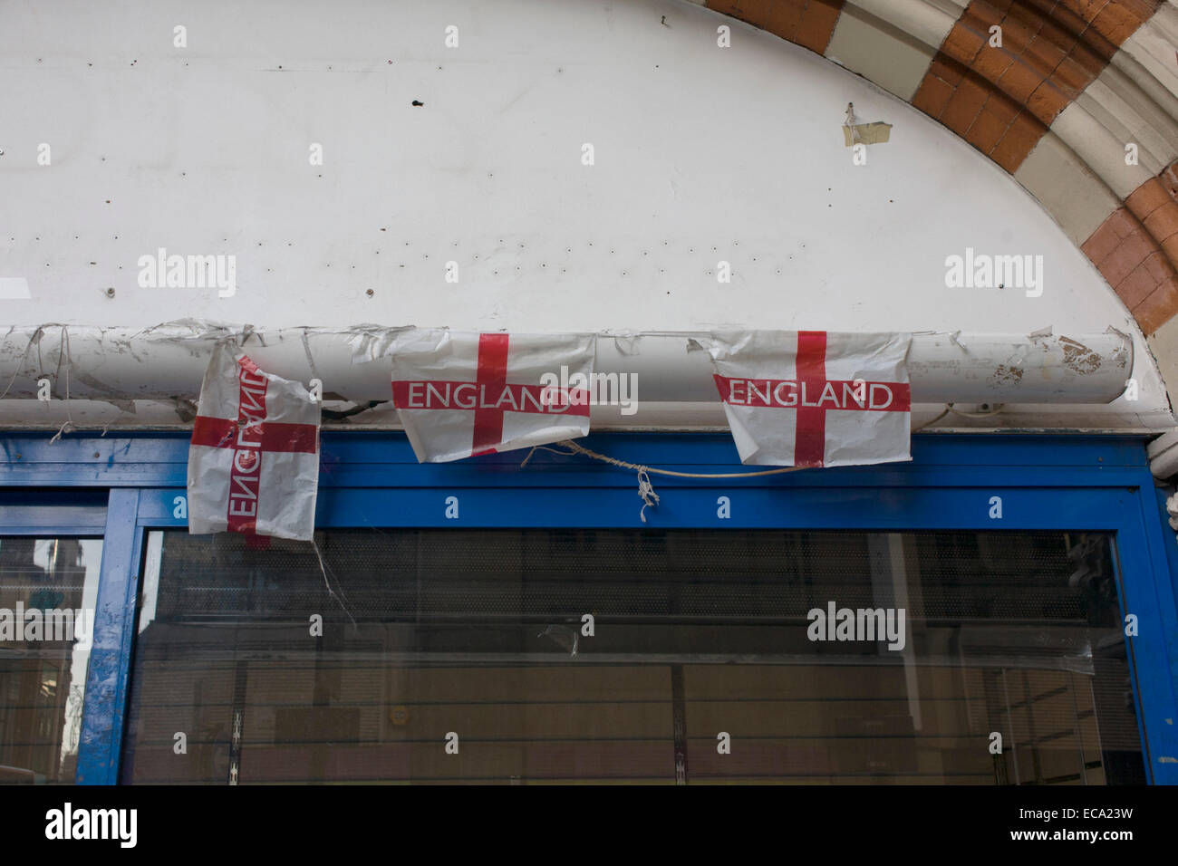 Dystopian detail of three torn English flags above the window of a ...