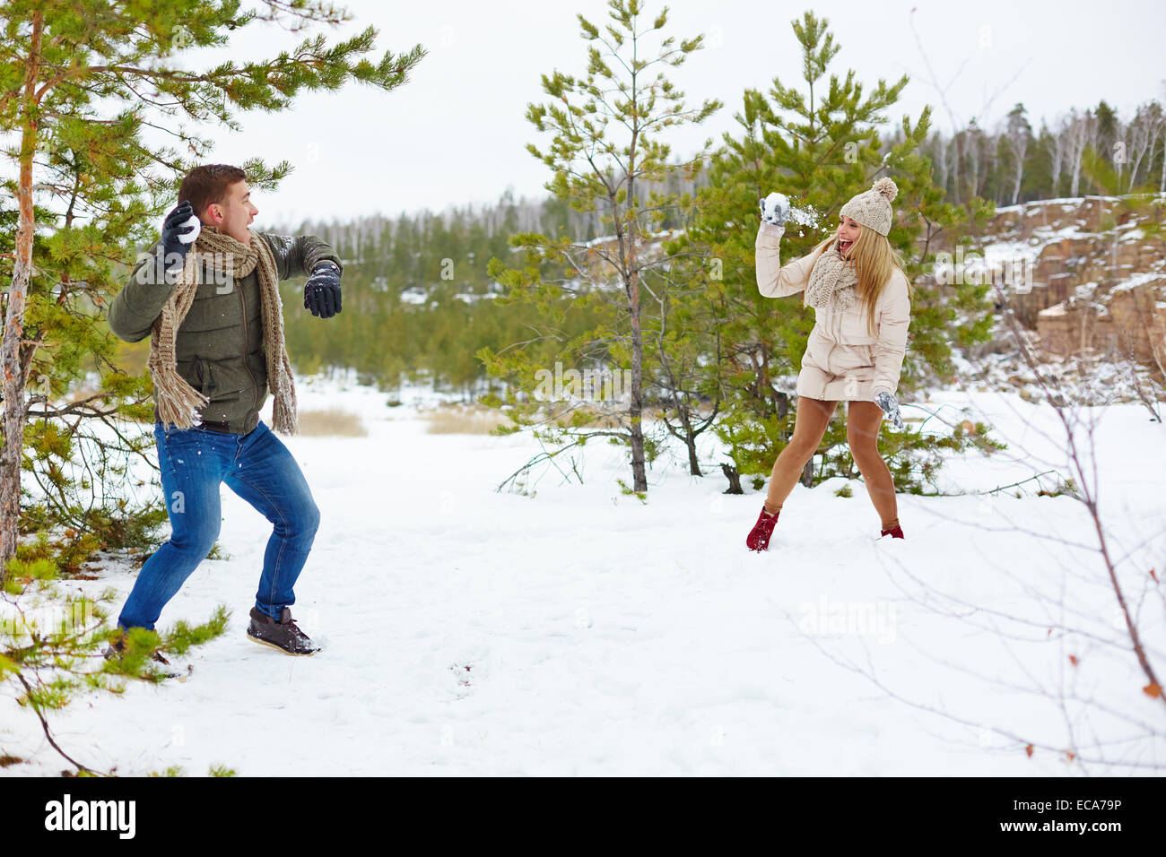 Young guy and his girlfriend throwing snowballs at one another in the ...
