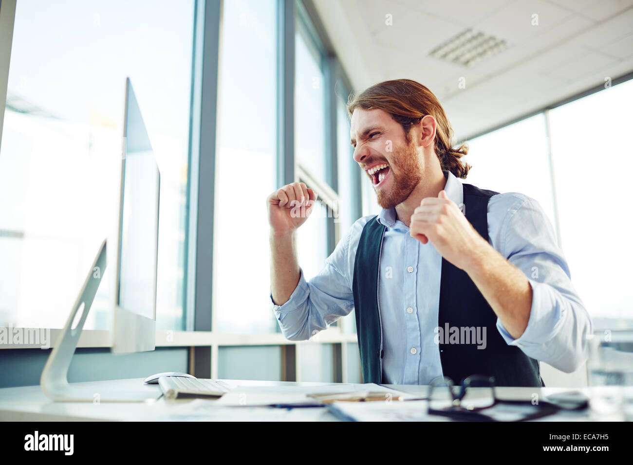 Ecstatic young businessman expressing great satisfaction while looking ...