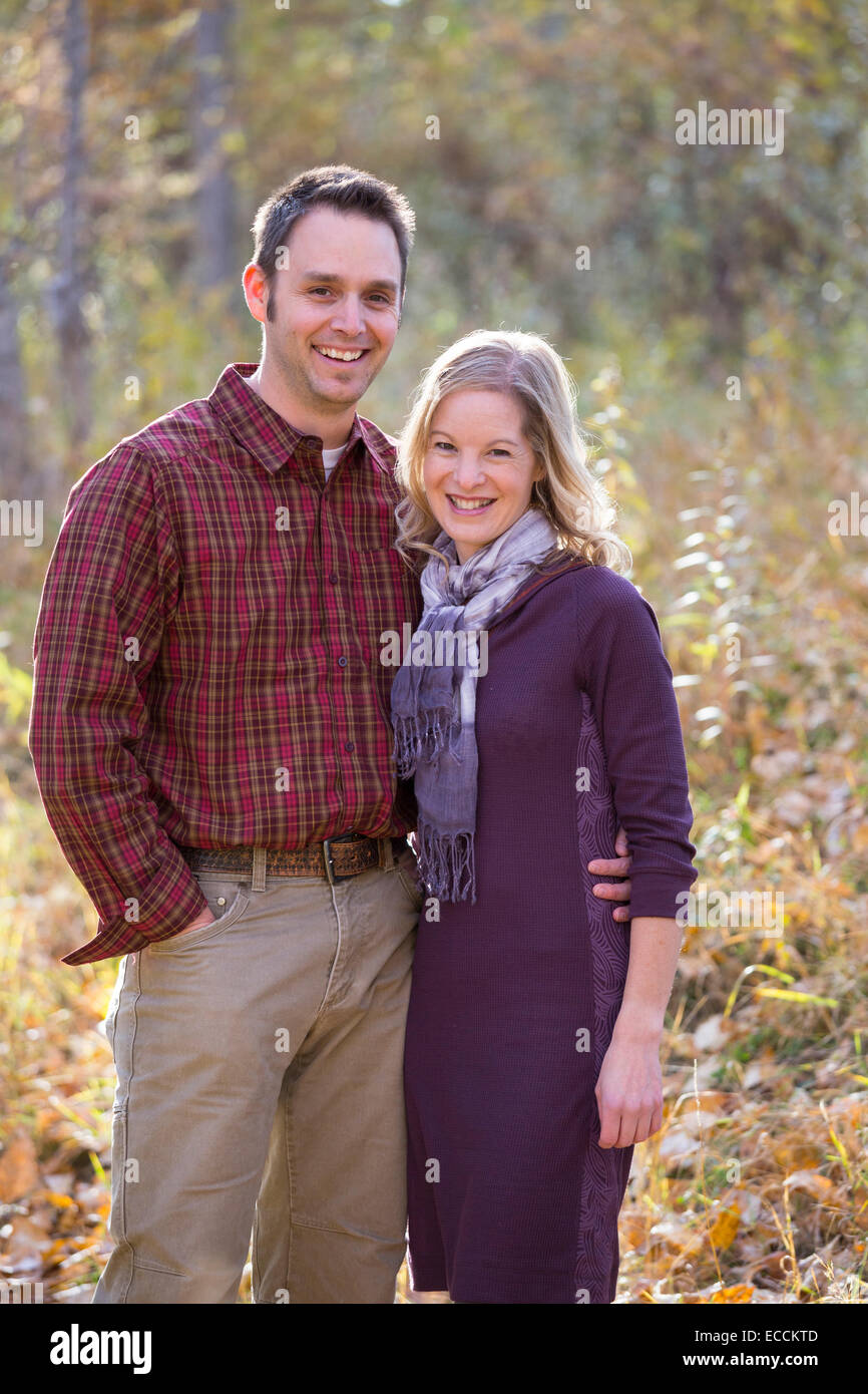 A husband and wife smile during a fall time family photo session in ...