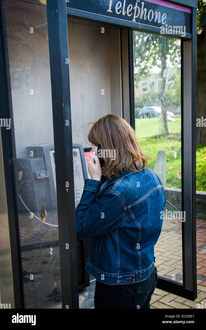 Girl in denim jacket making emergency phone call from call box Stock ...