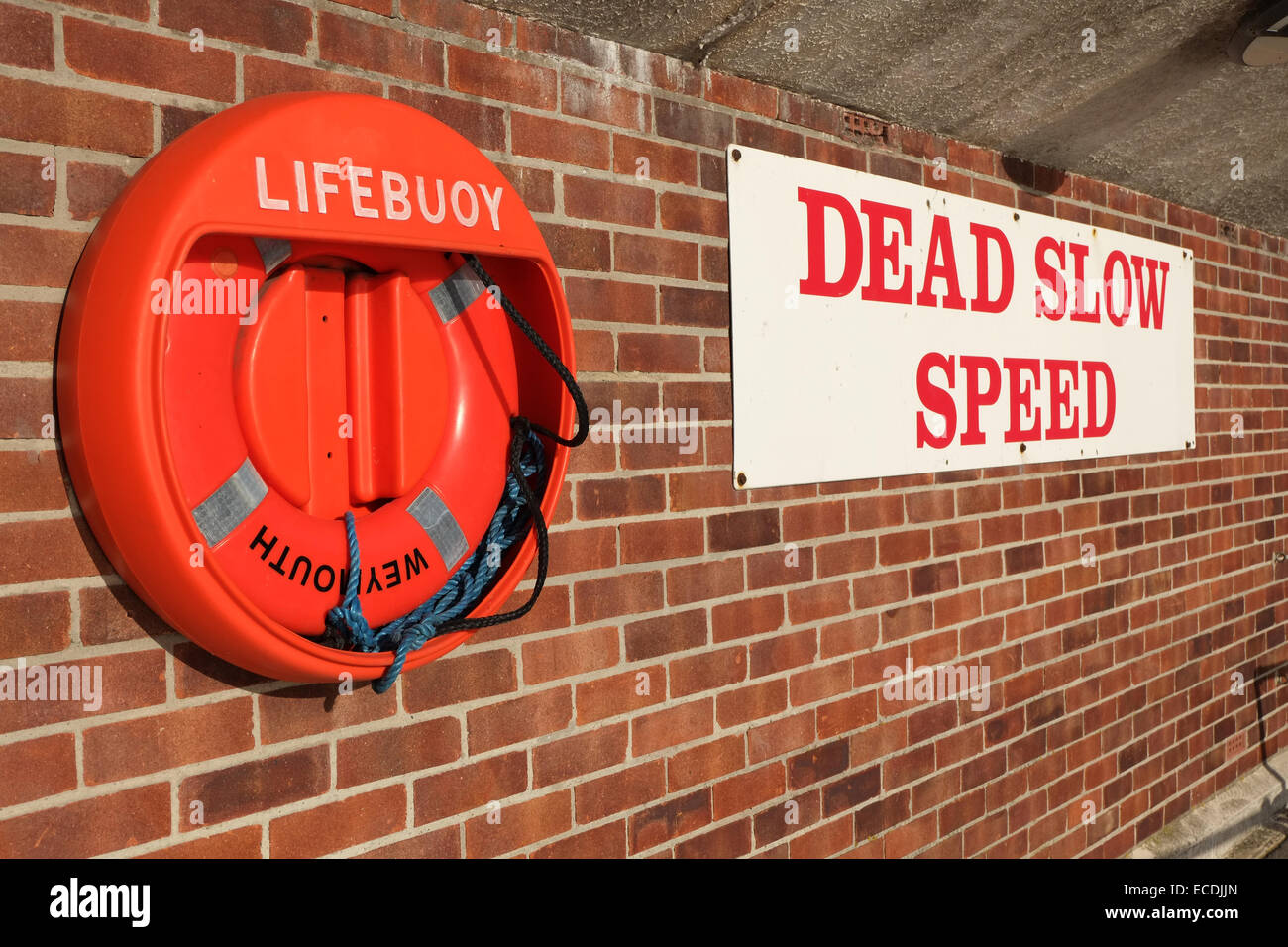 Large dead slow speed sign and Lifebuoy, in Weymouth harbour to slow ...