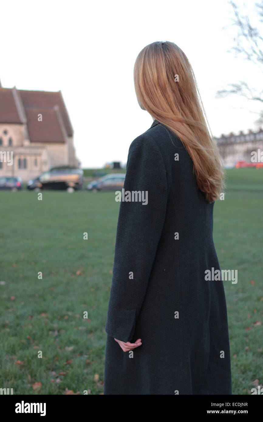 Rear view shot of a young woman standing looking into the distance in a ...