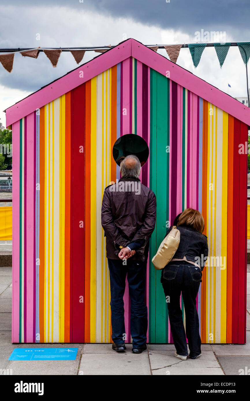 A Couple Look Through The Window Of A Beach Hut Installation, Festival ...