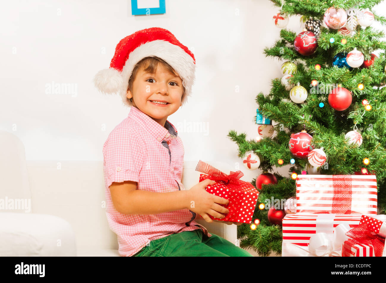 Little boy with present under New year tree Stock Photo - Alamy