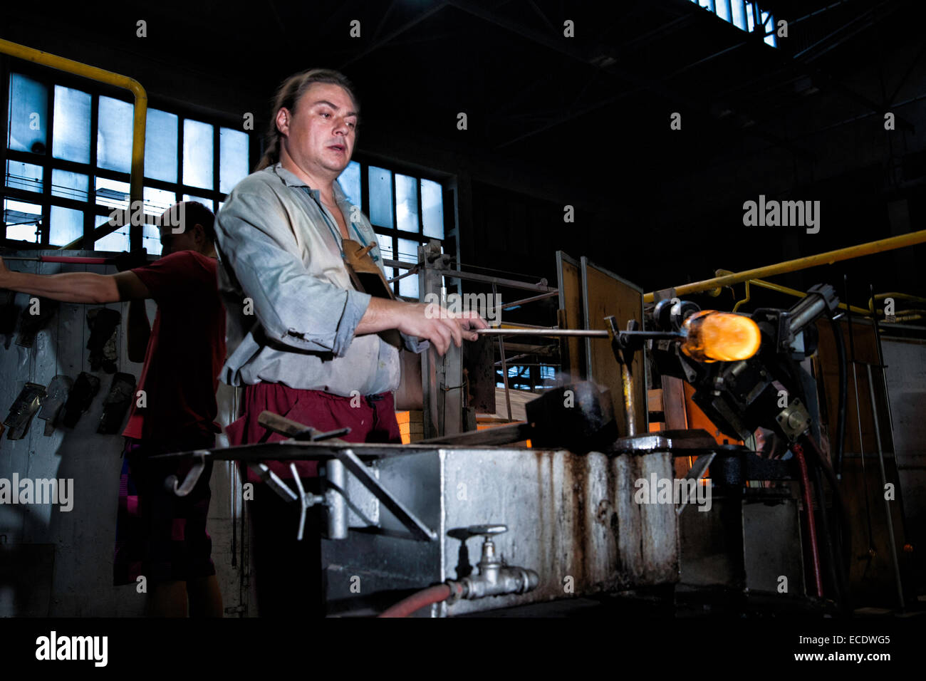 Male glass blower shaping blown glass into crystal goblets at Moser ...