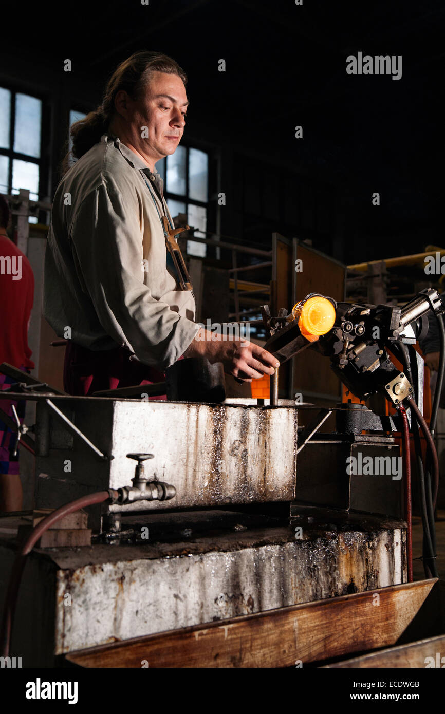 Male glass blower shaping blown glass into crystal goblets at Moser ...