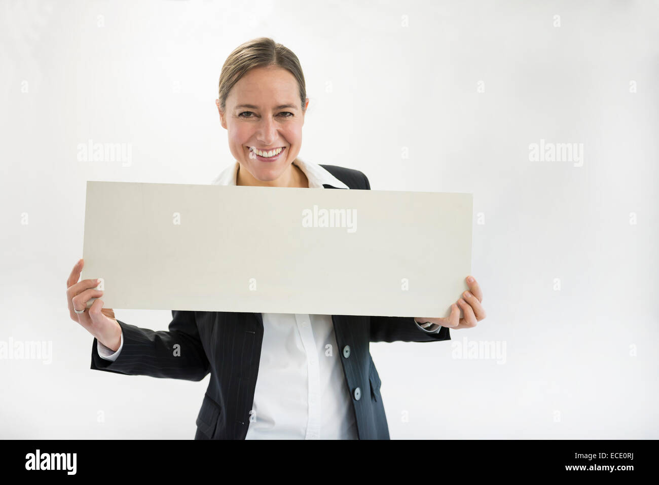 Portrait of businesswoman in black suit holding blank placard, smiling ...