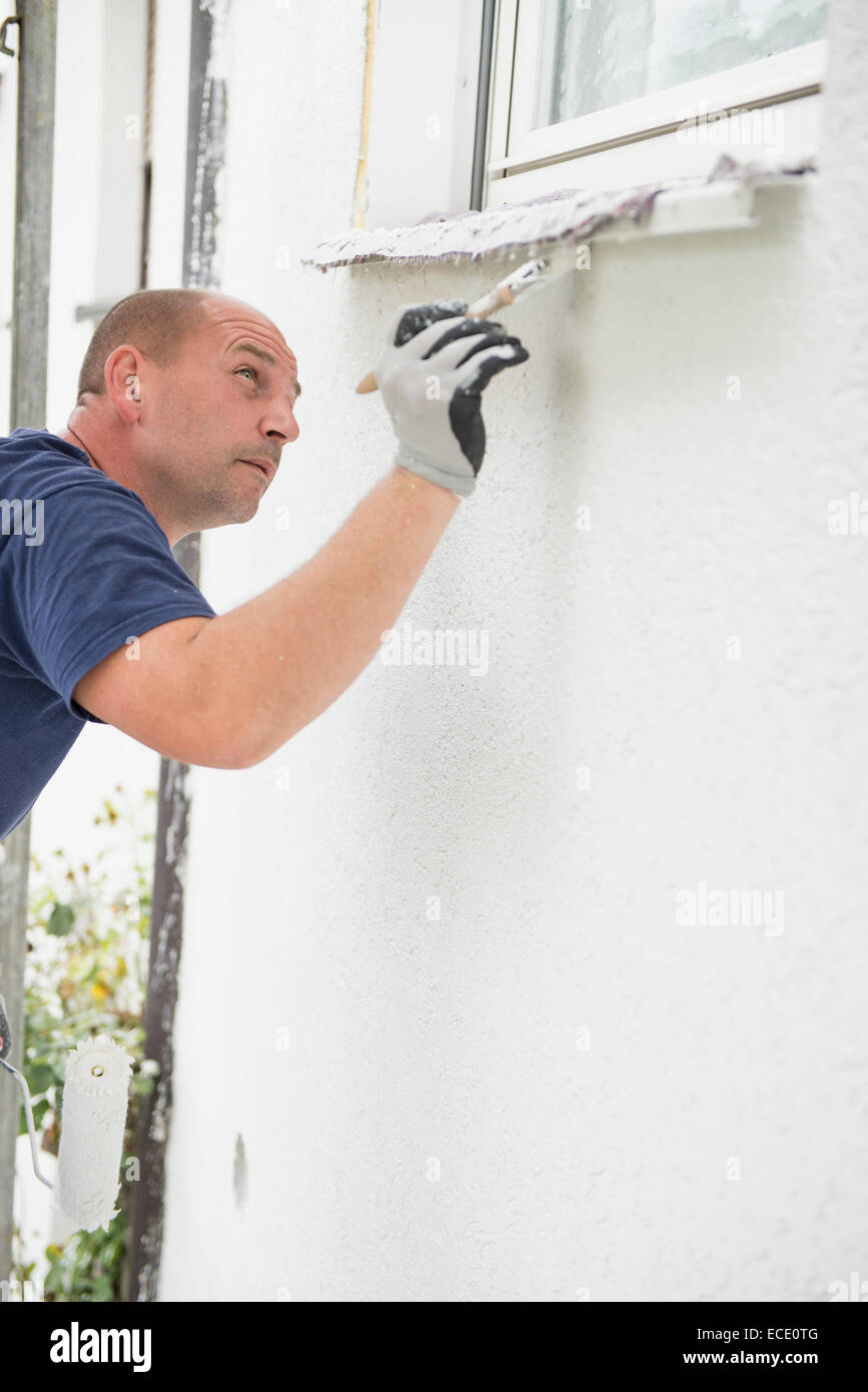 Repairing painting wall man house outside Stock Photo - Alamy