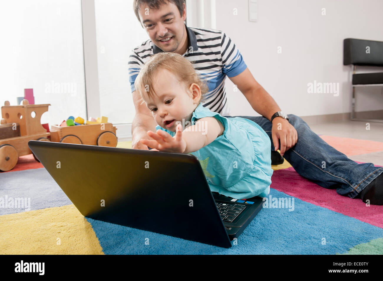 Baby father playing carpet laptop computer Stock Photo - Alamy