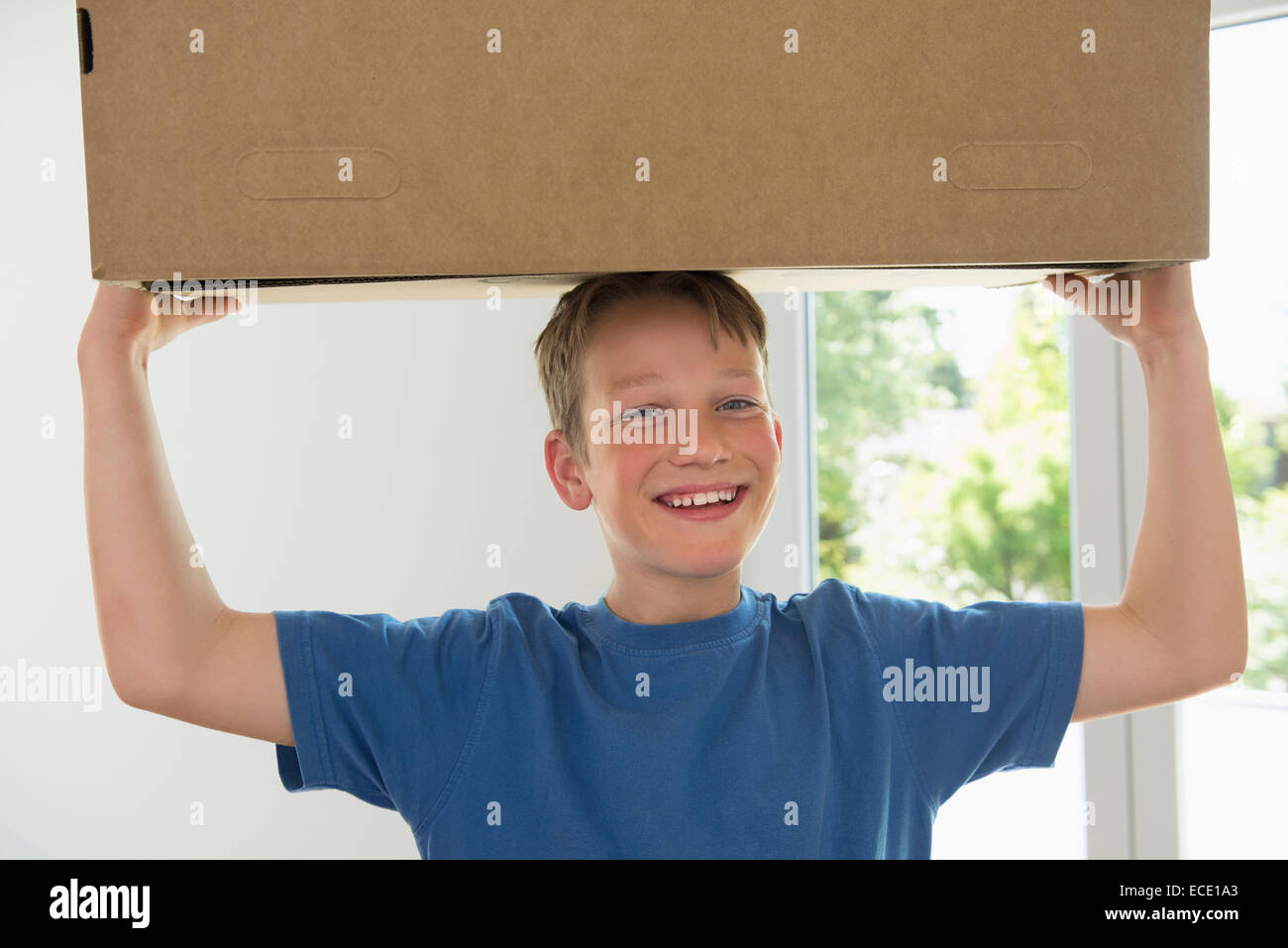 Young boy carrying box new apartment Stock Photo - Alamy