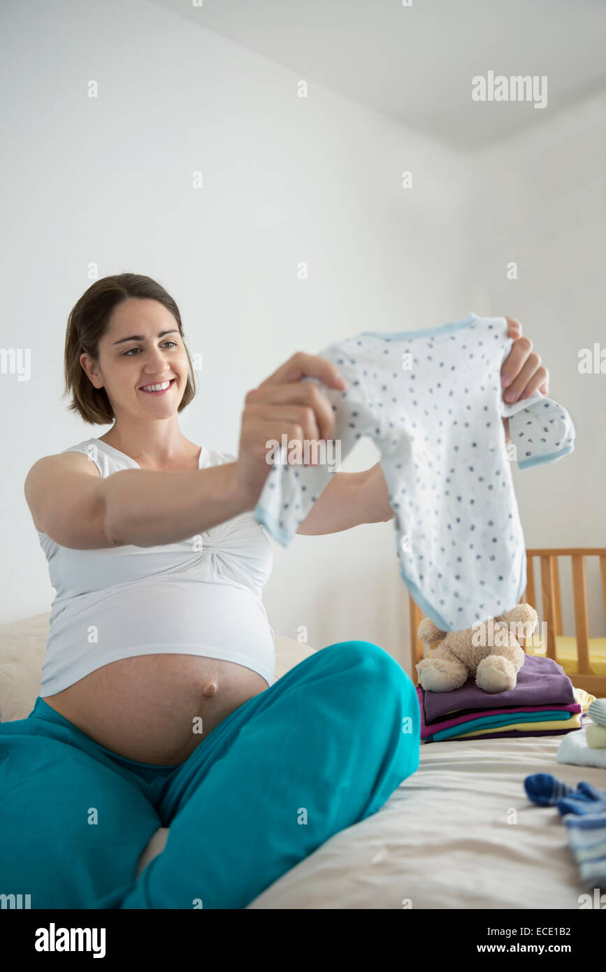 Pregnant woman holding packing baby clothes Stock Photo - Alamy