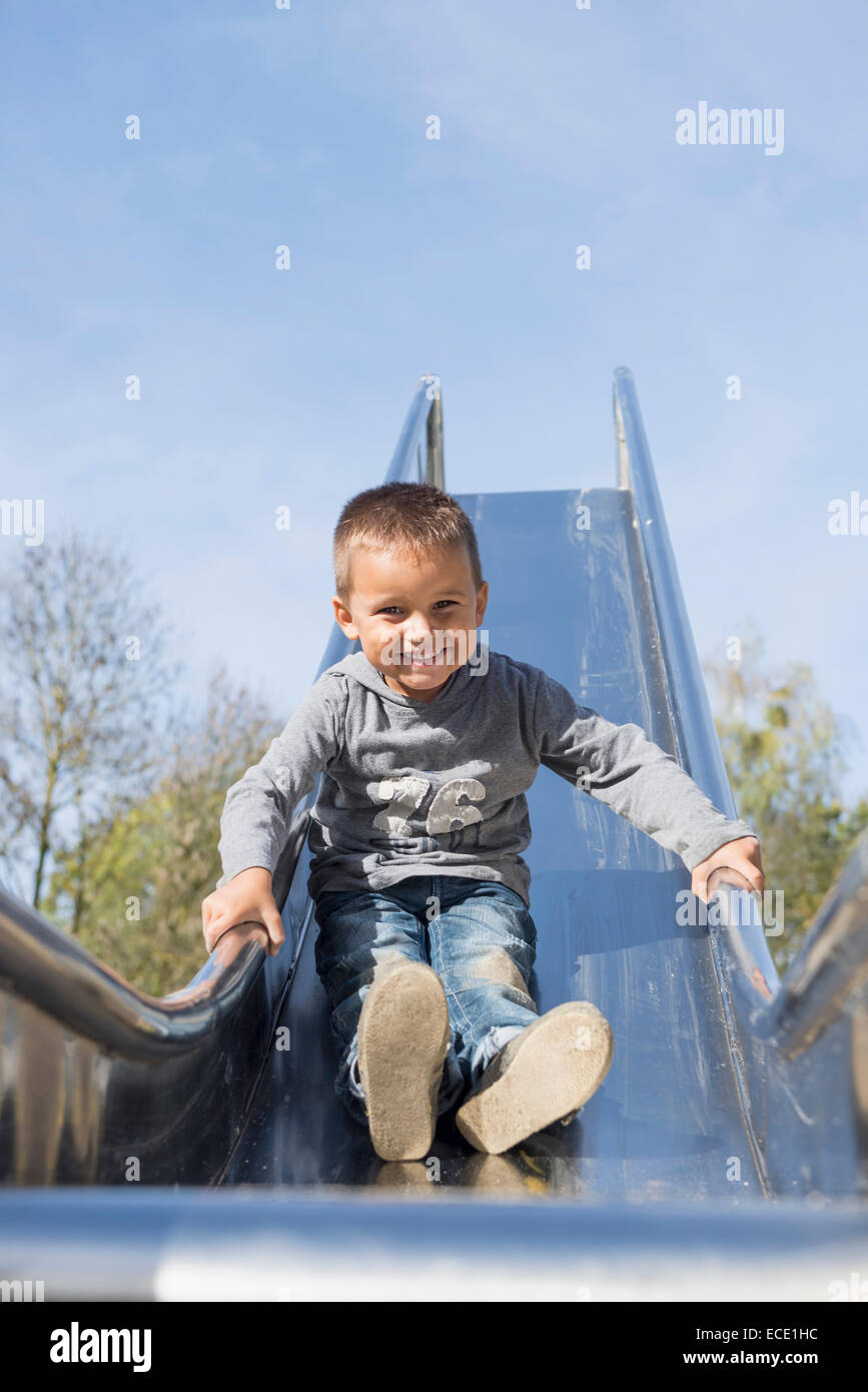 Portrait small young boy sliding playground slide Stock Photo - Alamy