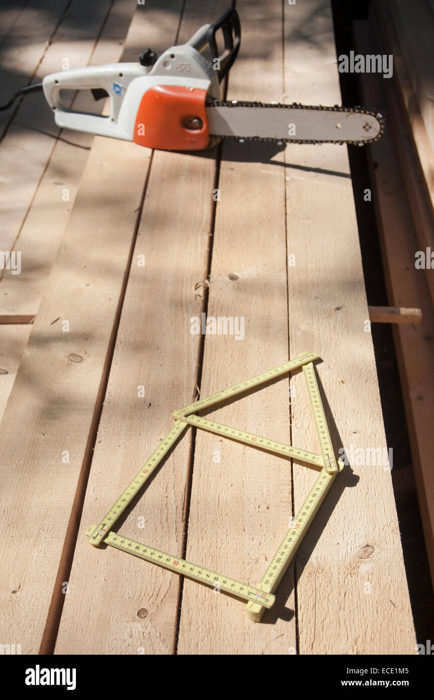 Folding ruler shaped as house with electric saw on wood Stock Photo - Alamy