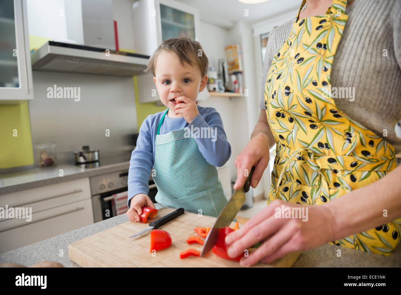 Son nibbling vegetables while mother is cutting them Stock Photo - Alamy