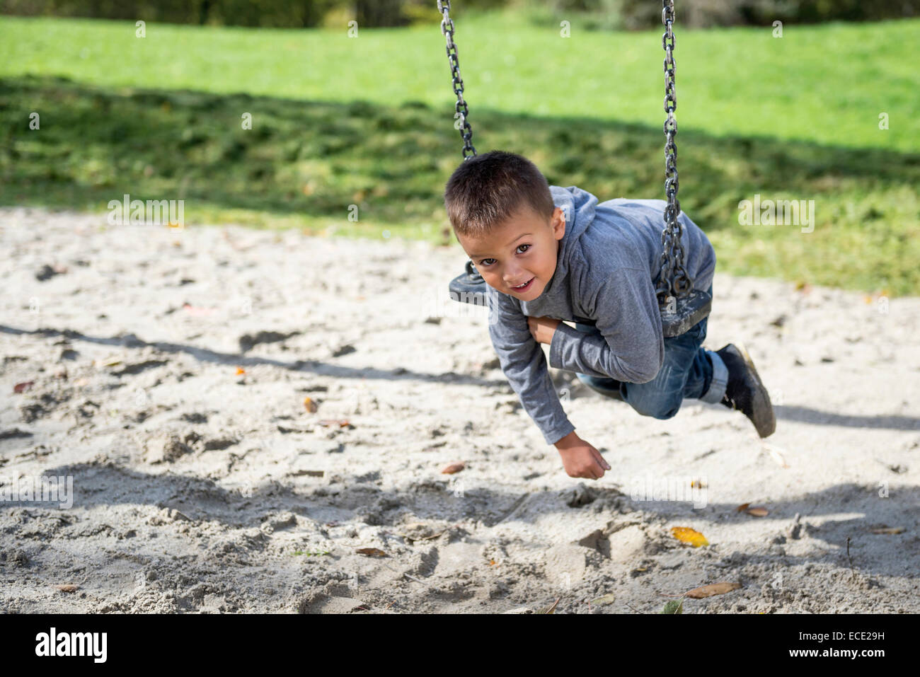 Young small boy swinging playground swing Stock Photo - Alamy