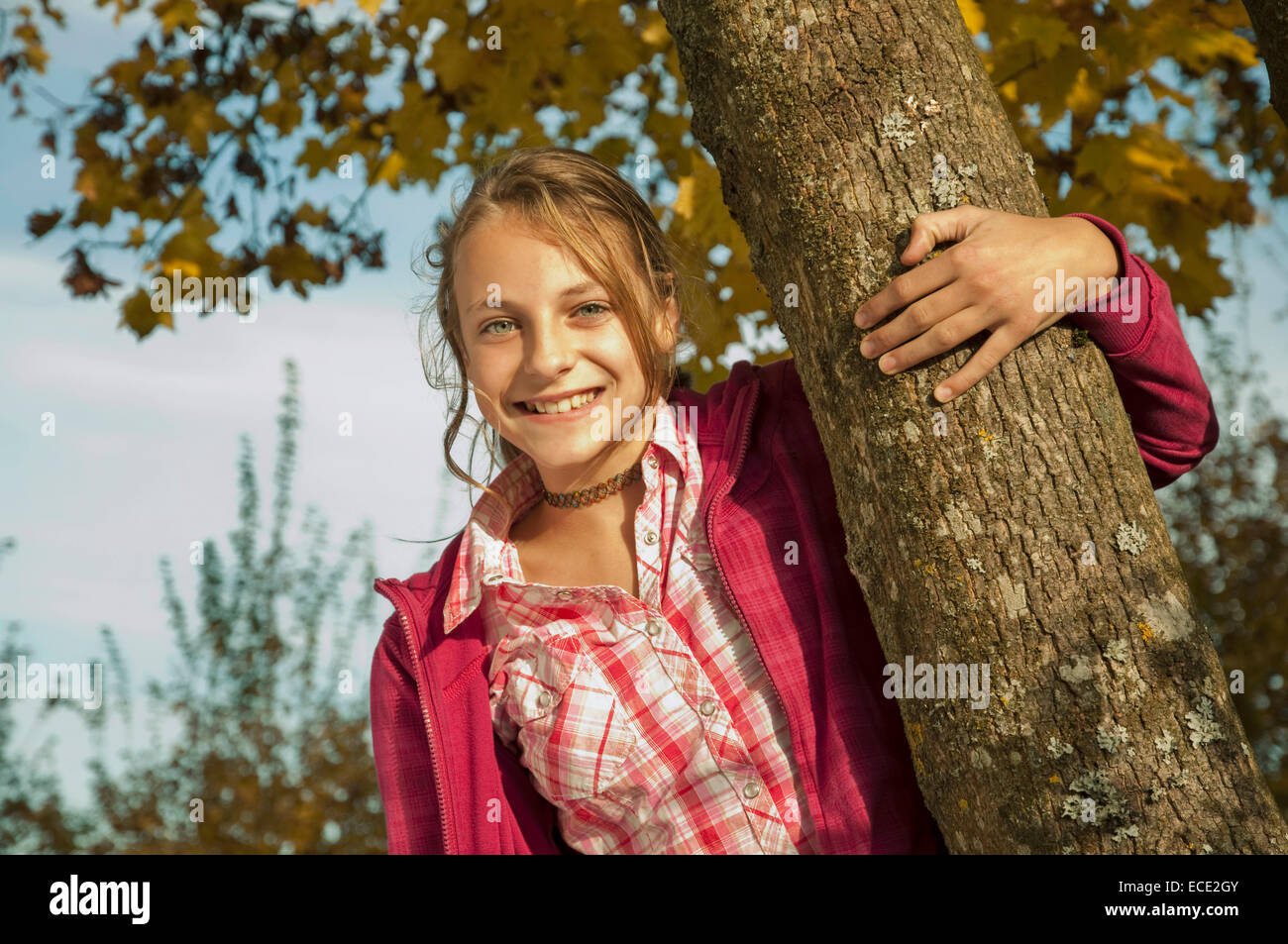 Girl holding tree trunk, smiling, portrait Stock Photo - Alamy
