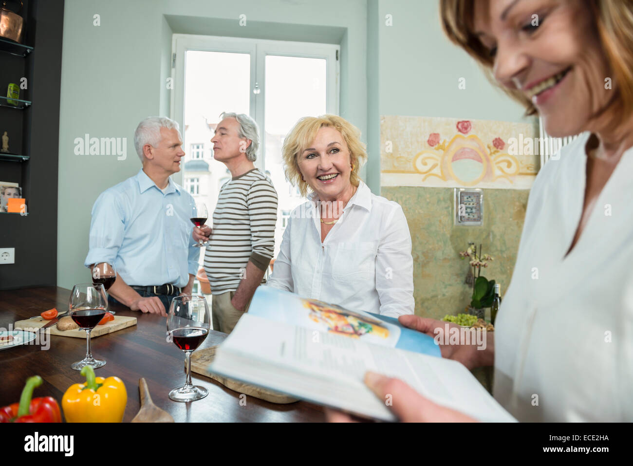 Senior group friends kitchen cooking drinking wine Stock Photo - Alamy