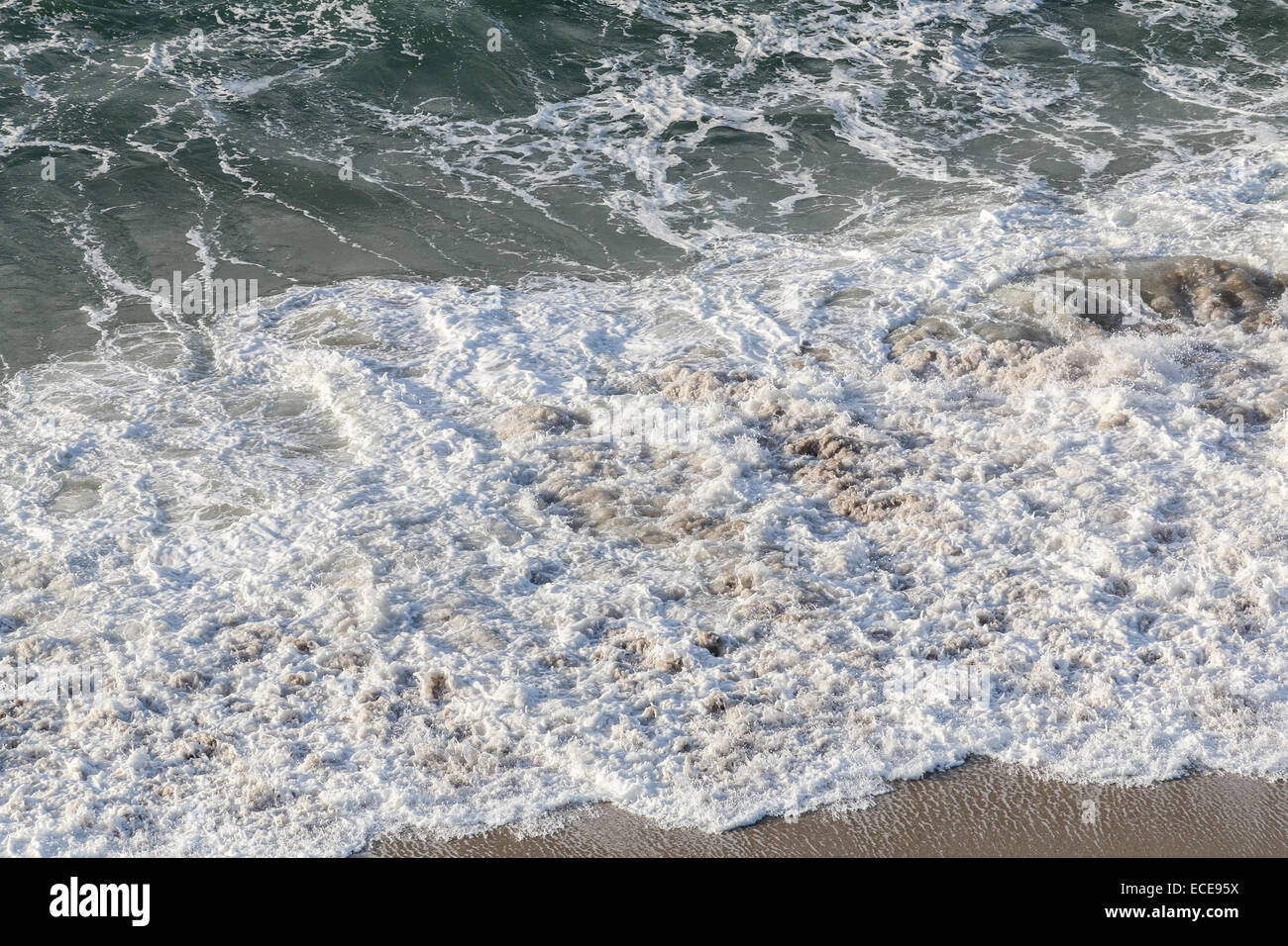 Waves and sea foam breaking on a beach in England Stock Photo - Alamy