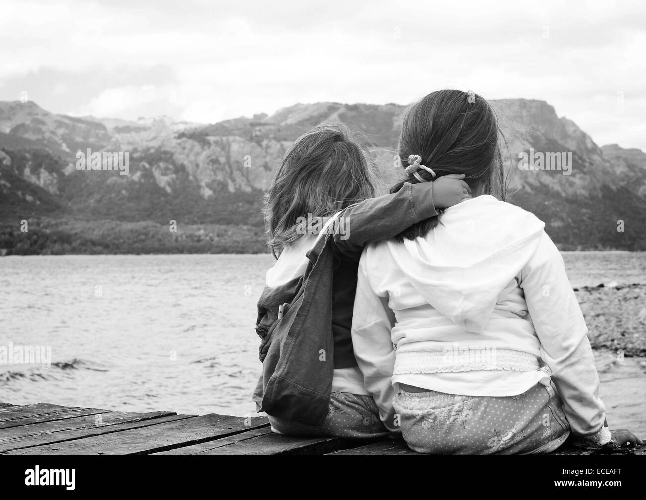 Two friends sitting side by side on jetty hi-res stock photography and ...