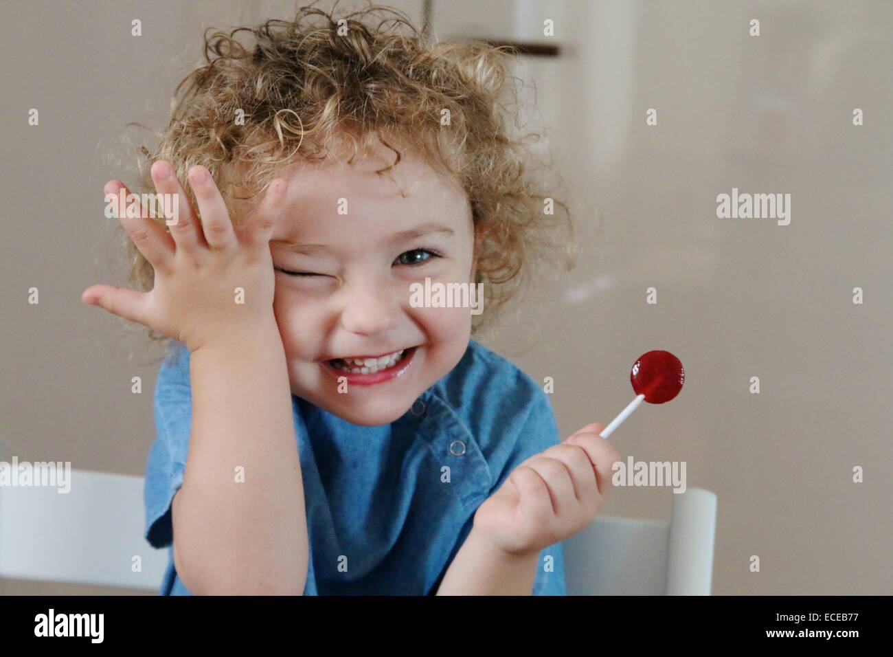 Happy girl eating a lollipop and touching her face Stock Photo - Alamy