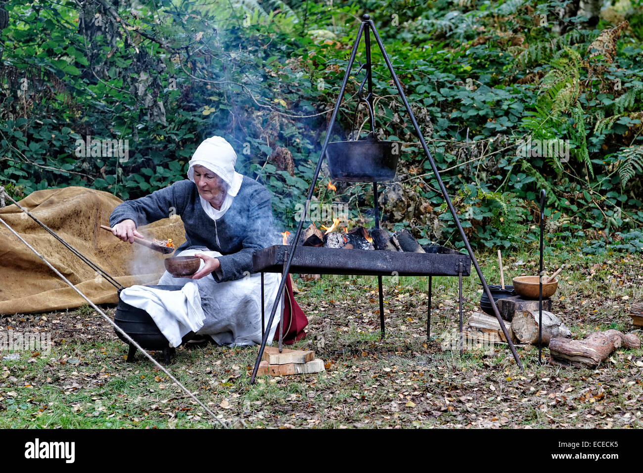 Dishing up pottage with meat cooked in an iron pot hung from a tripod ...