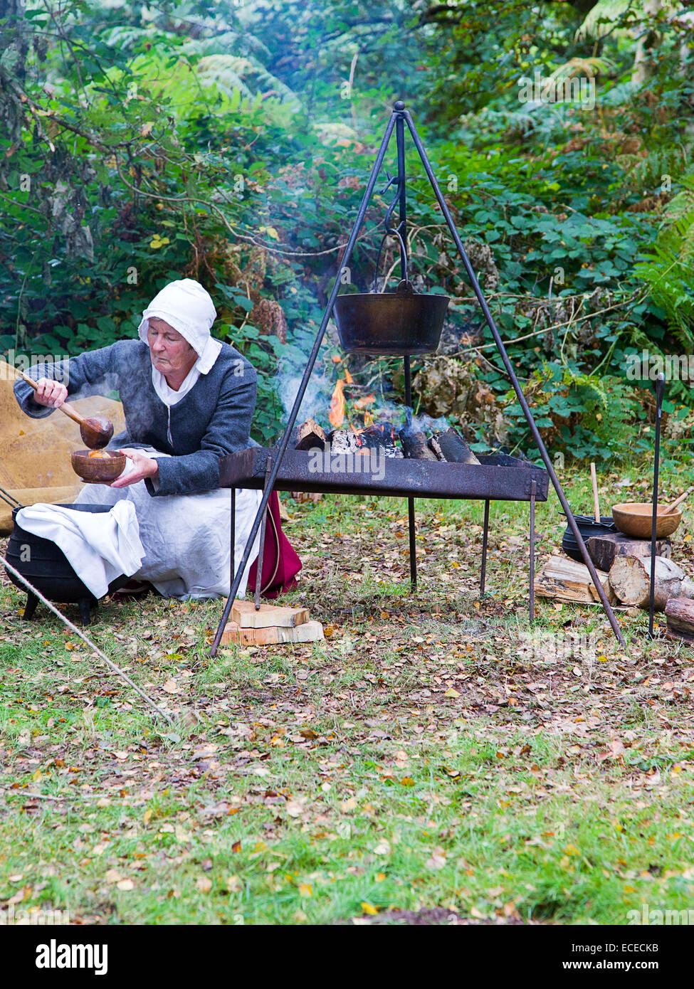 Dishing up pottage with meat cooked in an iron pot hung from a tripod ...