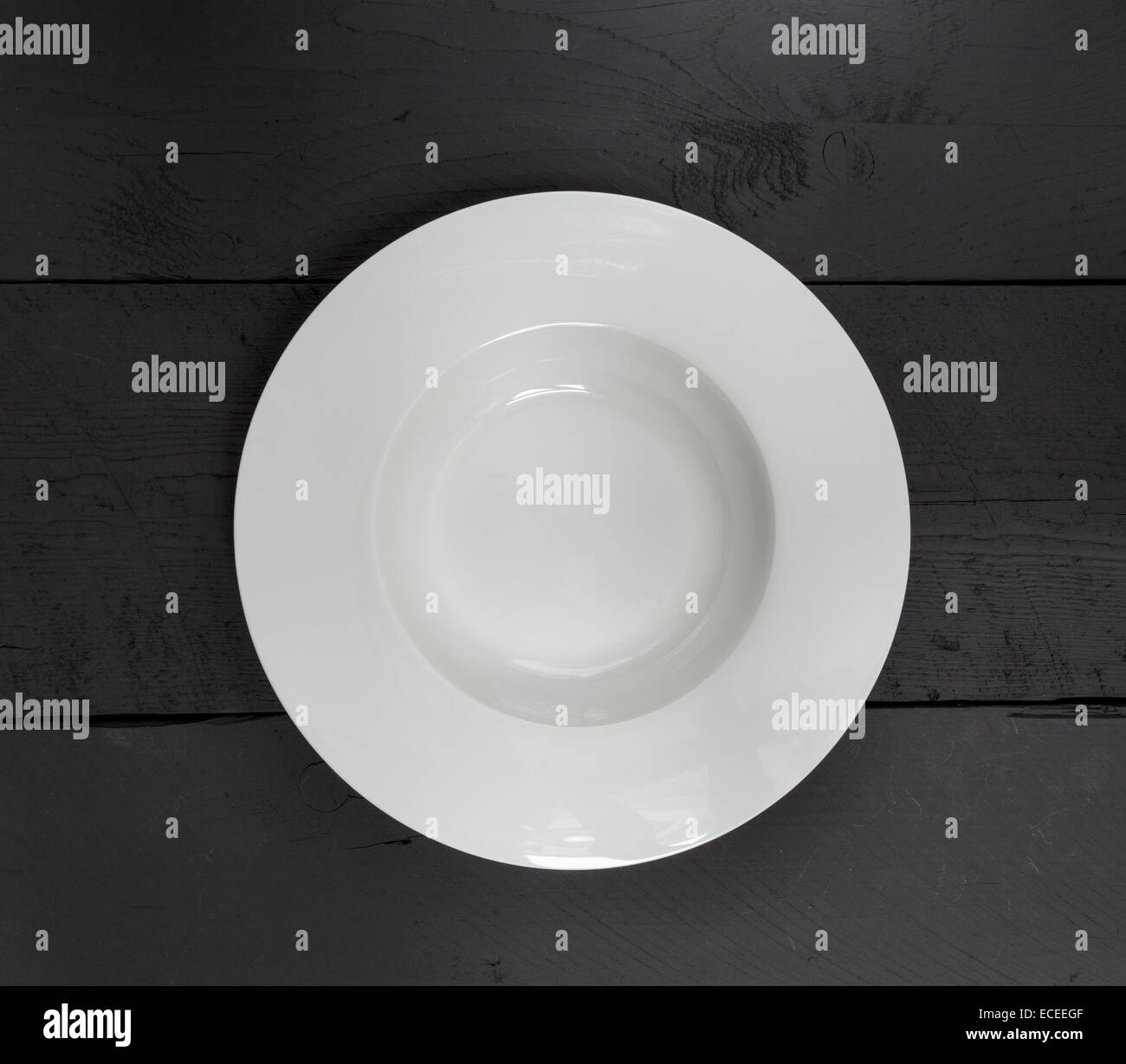 Empty deep plate on wooden black background Stock Photo - Alamy
