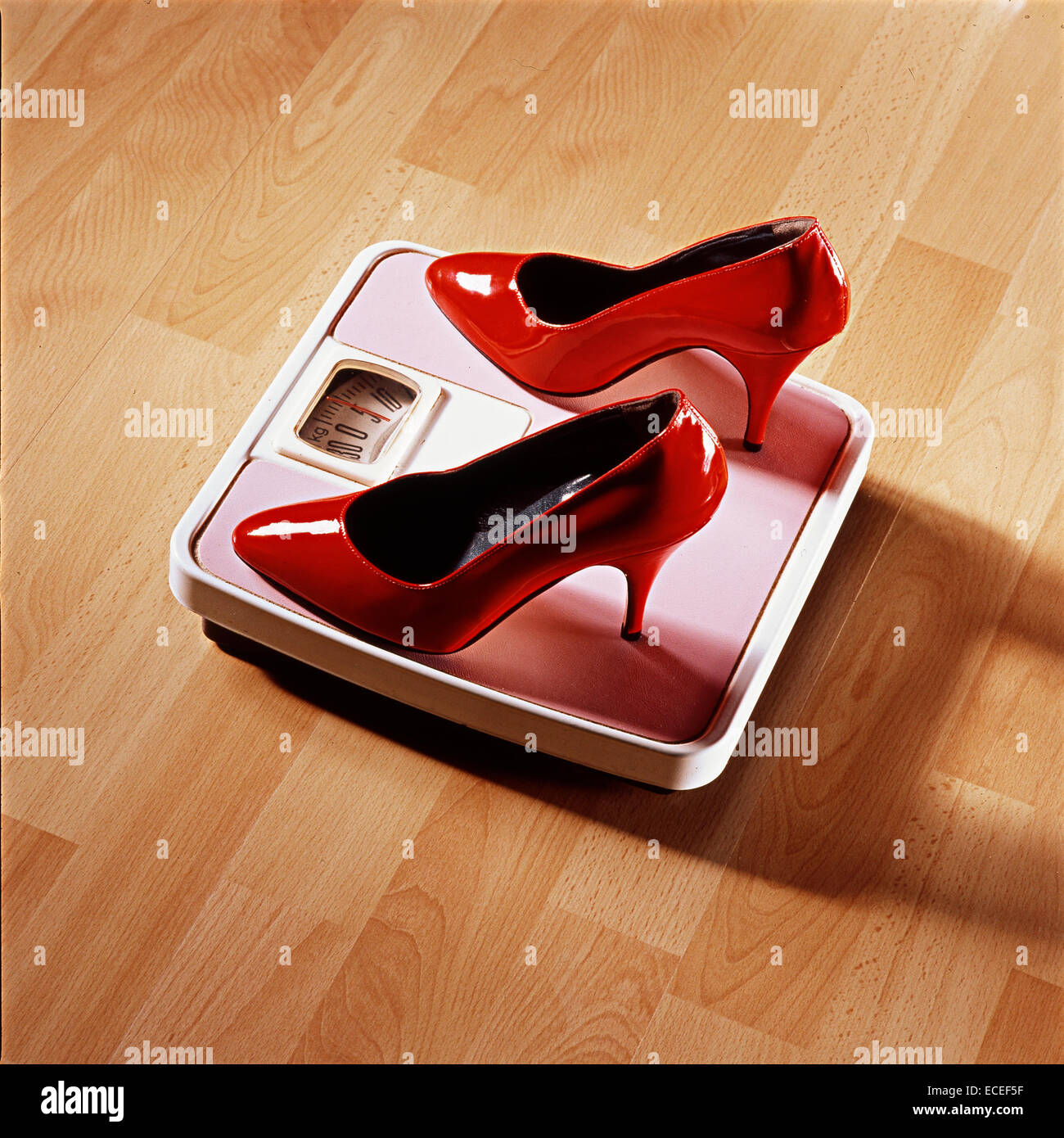 Red heel shoe on the pink weight scale isolated on white background ...