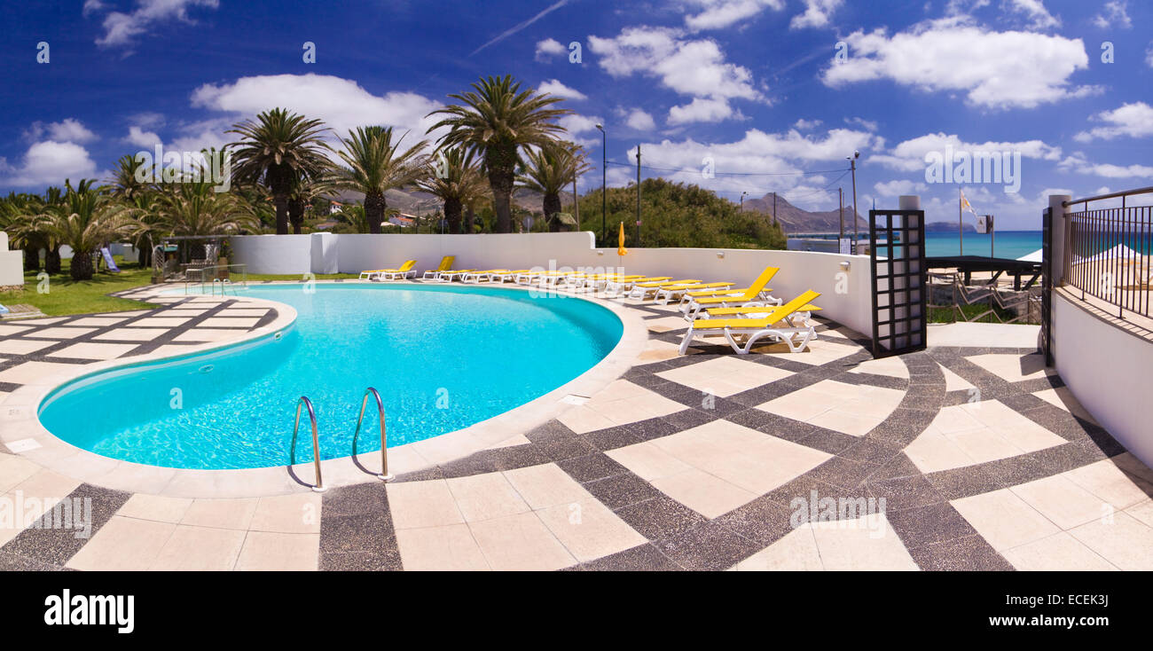 Hotel swimming pool surrounded by deck chairs on the island of Porto ...