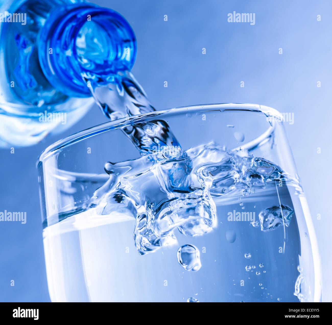 Pouring water from bottle into glass in blue toning Stock Photo - Alamy