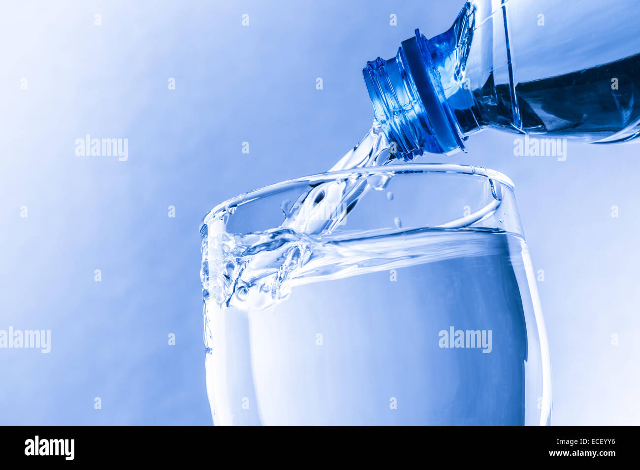 Pouring water from bottle into glass in blue toning Stock Photo - Alamy
