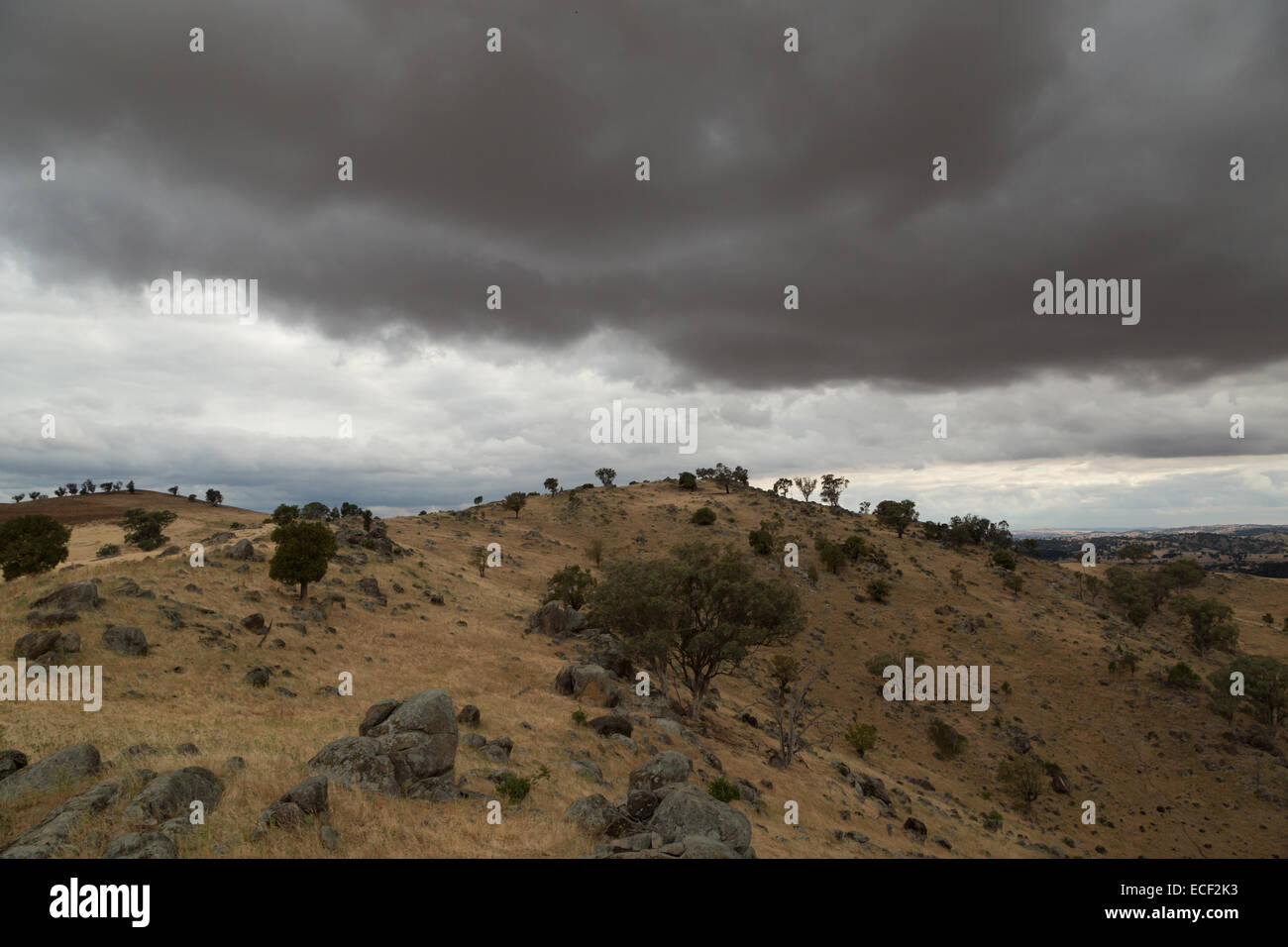 A photograph of some grey rain clouds above a very dry drought affected ...
