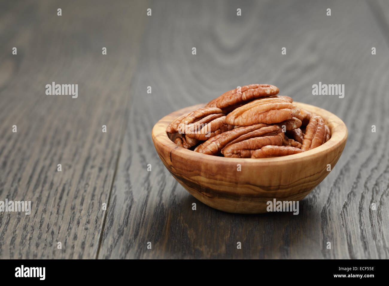 dried pecan nuts in olive bowl on wood table, simple photo Stock Photo ...
