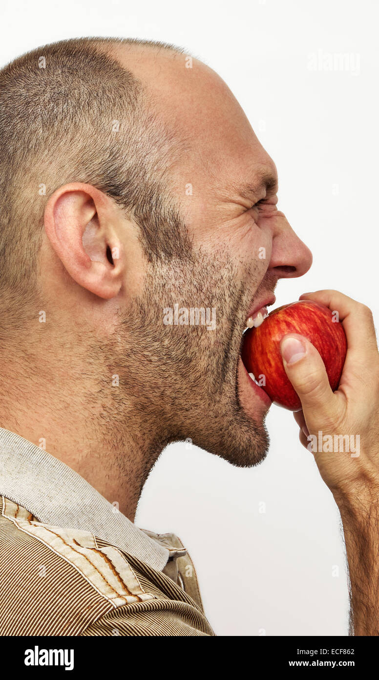 Man expressively bites red apple Stock Photo - Alamy