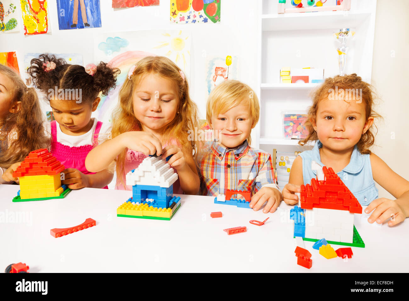 Group of kids playing building houses with plastic blocks sitting ...