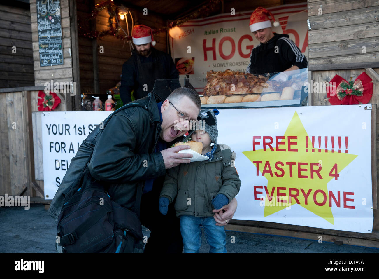 Father and son enjoy a Hog Roast roll from a Christmas Market outside ...