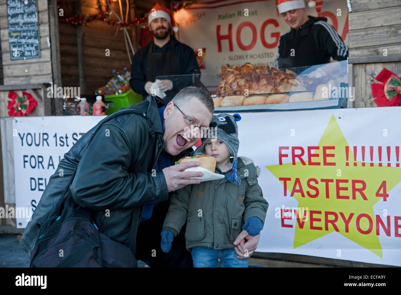 Father and son enjoy a Hog Roast roll from a Christmas Market outside ...