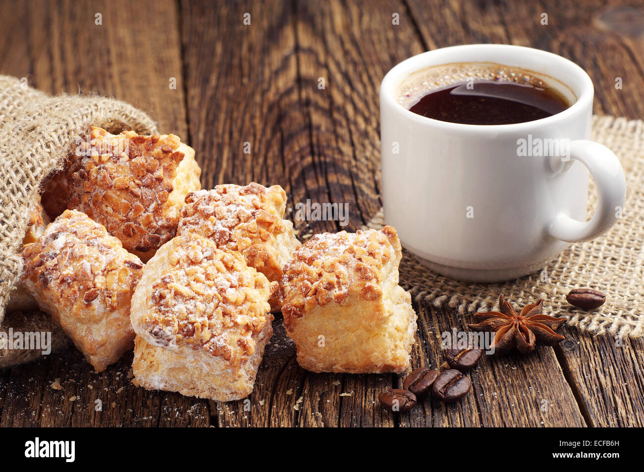 Cup of hot coffee and puff cookies with nuts on vintage wooden table ...